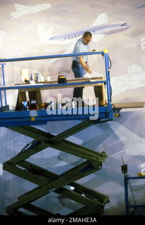 An aviation artist, paints a mural picture of aircraft, in flight, at ...