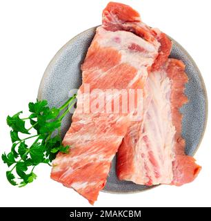 Raw meaty pork ribs slabs on plate with fresh greens Stock Photo - Alamy