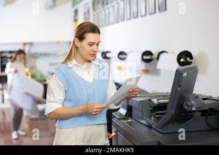 Technician operator calibrating plotter machine, typing on computer ...