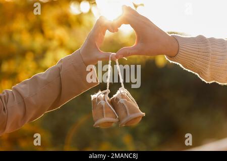 Man and pregnant wife are doing heart gesture with hands and holding ...