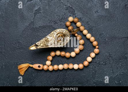 Aladdin lamp of wishes and prayer beads for Ramadan on dark background ...