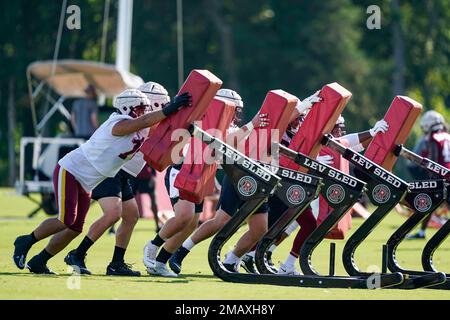 The Washington Commanders' offensive line runs a drill during practice ...
