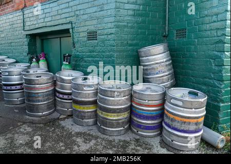 many polished silver metal beer kegs stored on street with grren ...