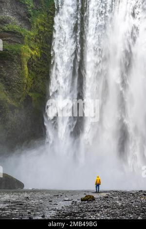 Man in front of large waterfall, Skogafoss, South Iceland, Iceland ...
