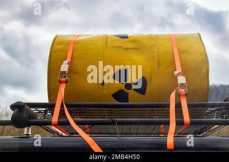 Yellow metal barrel with sign for radioactivity and poster, nuclear ...