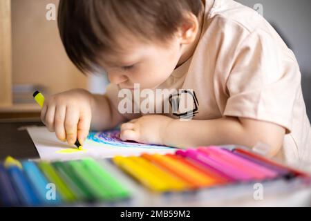 Enthusiastic male kid drawing multicolor rainbow paper sheet closeup ...