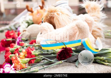 Toys and flowers lie at a trolleybus stop next to a house blown up by a ...