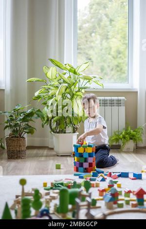 Confident male kid building fortress tower architecture and forest with ...