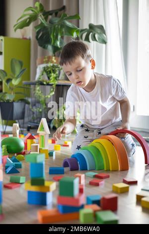 Funny baby boy playing multicolored arch Montessori wooden material ...