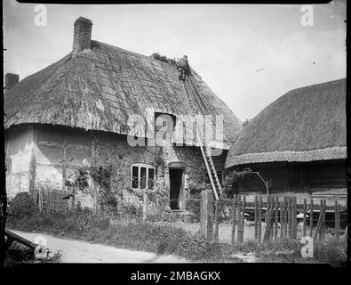 Wootton Rivers, Wiltshire, 1923. A thatcher working on the roof of an ...