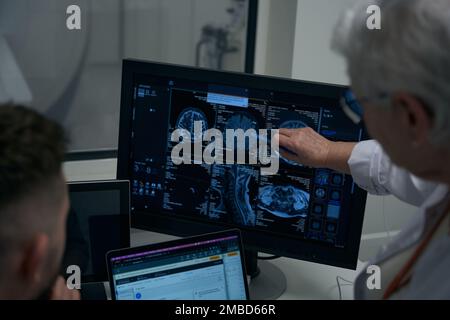 Elderly female doctor and her colleague reviewing brain CT scan results ...
