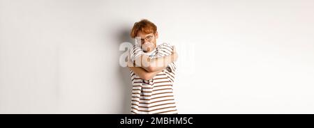 Reluctant young man with messy red hair unwilling do something, hugging ...