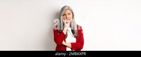 Troubled asian businesswoman in red blazer and lips, pouting and ...