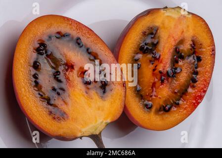 A Tamarillo fruit (Solanum betaceum) sliced open to show the two halves ...