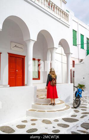 White Cycladic house with columns and red door, alleys of the old town ...