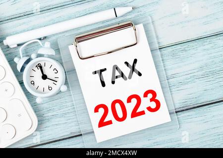 Tax 2023 text on clipboard with pen and calculator on wooden background ...