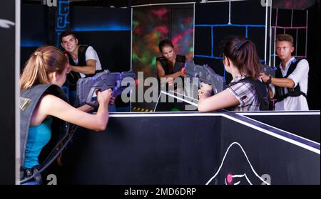 Excited people playing enthusiastically laser tag game Stock Photo - Alamy