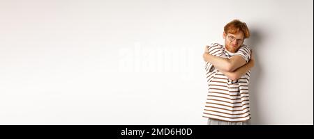 Reluctant young man with messy red hair unwilling do something, hugging ...