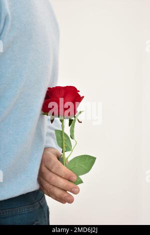 Photo of man holding a red rose behind his back Stock Photo - Alamy