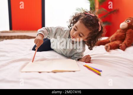 Adorable hispanic girl drawing on notebook lying on sofa by christmas ...