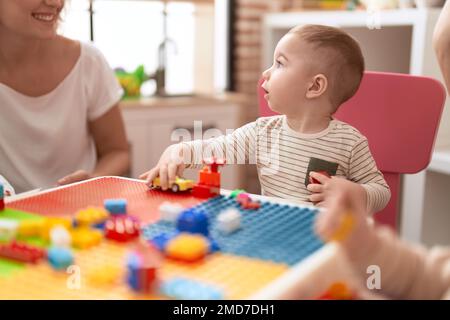 Adorable toddler playing with car toy sitting on table at kindergarten ...