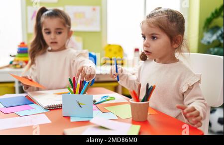 Adorable hispanic boy preschool student sitting on table drawing on ...
