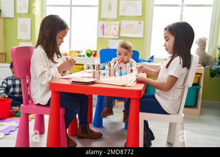 Adorable hispanic boy preschool student sitting on table drawing on ...