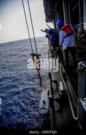 A MANTAS T-12 unmanned surface vessel (USV), front, operates alongside ...