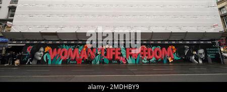 People walk past a mural highlighting the plight of women in Iran, on ...