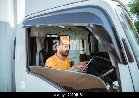 male driver in yellow uniform looking at clipboard to check Stock Photo ...