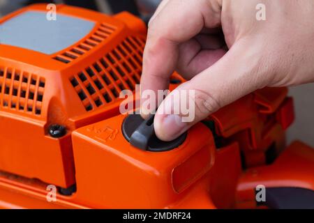 Unscrewing the cap of the fuel tank of the chainsaw for refueling a ...