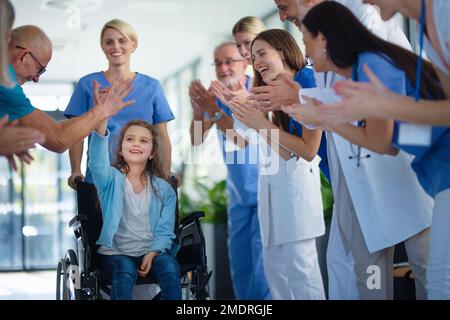 Medical staff clapping to little girl patient who recovered from ...
