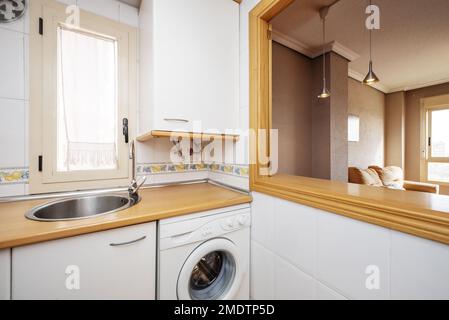 Corner of a small apartment kitchen with a hatch window to the living ...