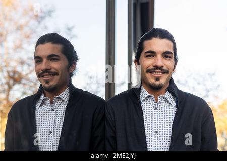 From below young Hispanic bearded man in casual outfit and eyeglasses ...