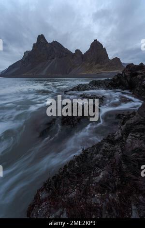 Picturesque scenery of waving sea washing rough shore near high snowy ...