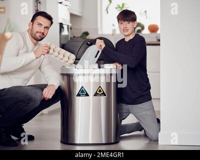 Father and son sorting waste paper and plastic into a sorting bin Stock ...
