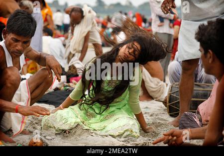 A priest performs exorcism on a Hindu devotee by immersing her in the ...