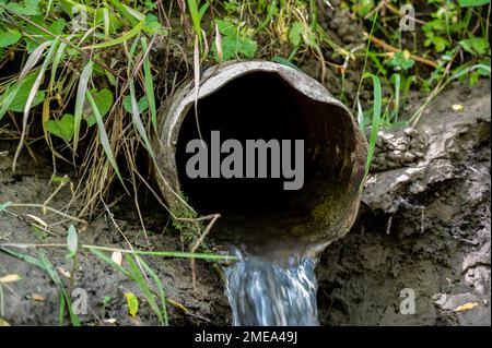 Farm field tile outlet with water flowing. Water drainage, flooding ...