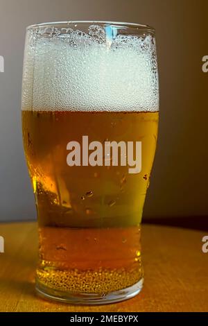 Refreshing amber ale with light foam in a clear drinking glass resting ...