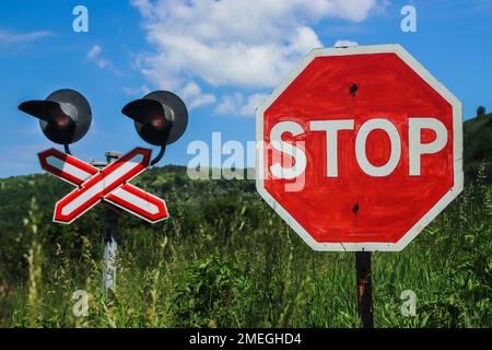 stop sign in front of a railway crossing on a background of blue sky ...