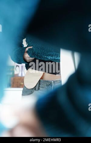 A female colon cancer survivor looking at the ostomy bag in the mirror ...