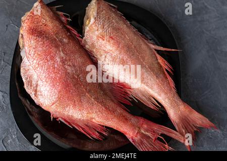 Two frozen headless carcasses of red sea bass Stock Photo - Alamy