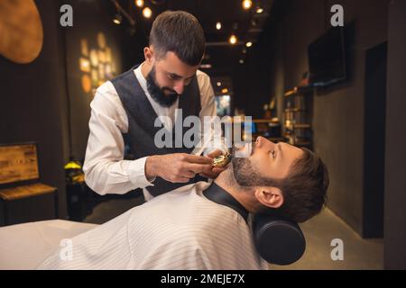 Professional barber carefully trimming the clients beard Stock Photo - Alamy