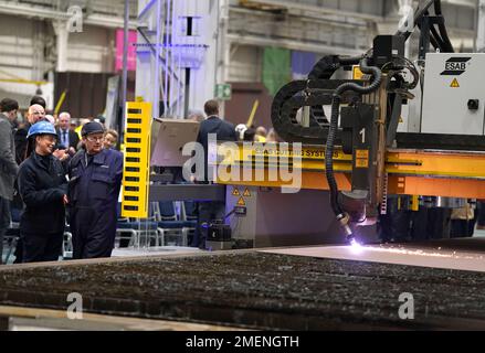 Workers look on as the first cut of steel for the Royal Navy frigate ...