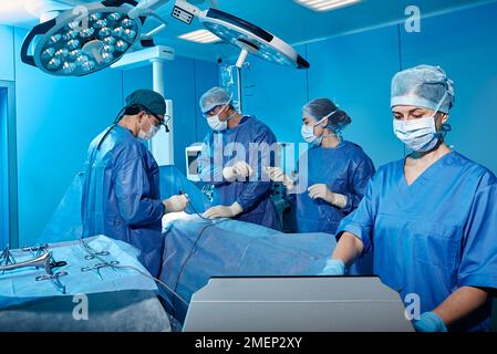 Operating theatre nurse wearing PPE with surgical scissors in hands standing in operation room ...