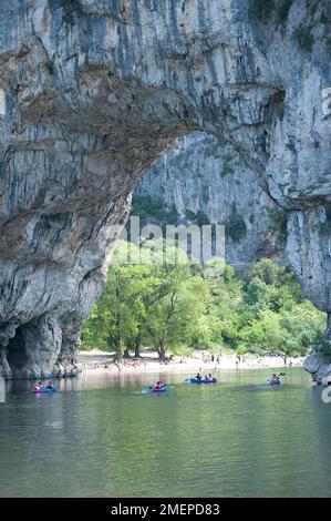 People canoeing under the Pont d'Arc, natural rock arch over river ...