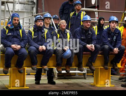 Workers look on as the first cut of steel for the Royal Navy frigate ...