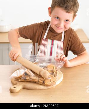 Crushing biscuits in plastic bag with rolling pin, to make biscuit ...