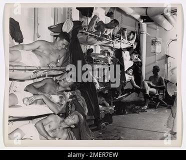 Coast Guardsmen aboard a transport ship are depicted holystoning the ...