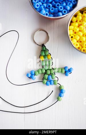Making beaded lizard key ring, threading beads onto cord Stock Photo ...